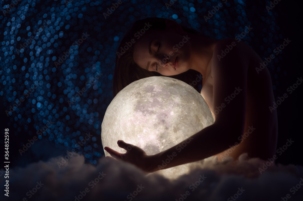 Female magic, astronomy and the zodiac. A beautiful girl holds the moon ...