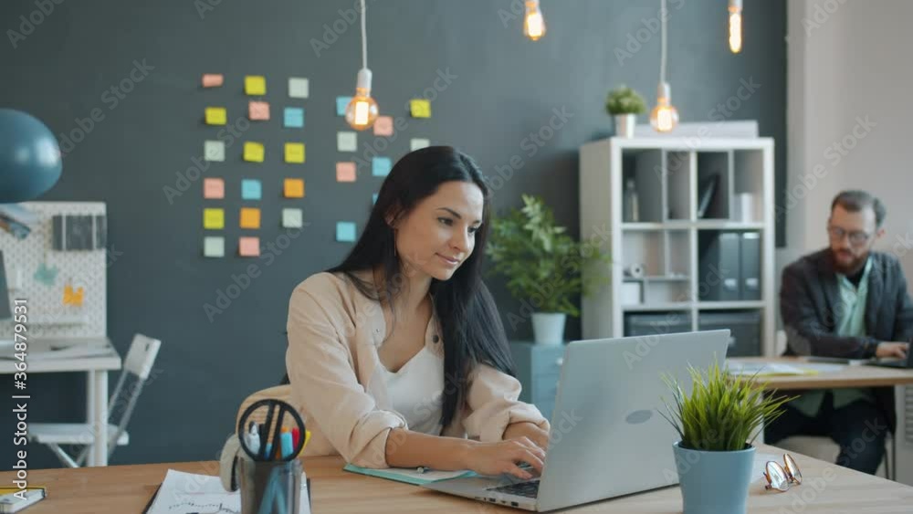 Young woman is working with laptop in creative shared office typing ...