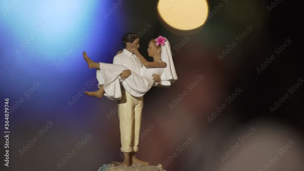 Bride and Groom wedding cake topper. Groom holds bride. Rack focus ...