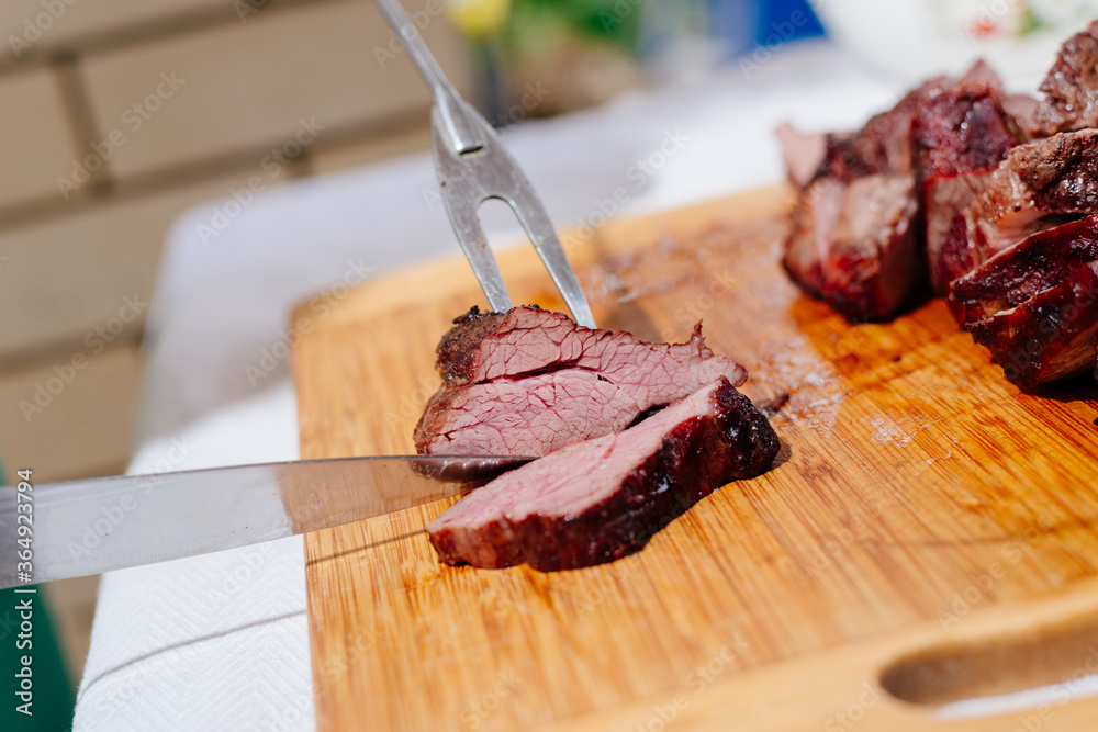 Beef steak with blood. Grilled beef with blood. The cook cuts the ...