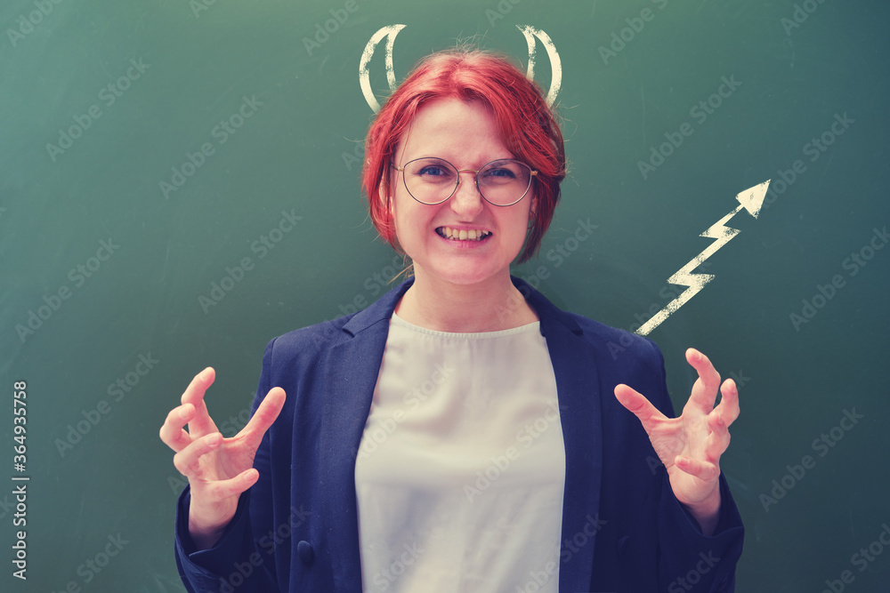 Woman teacher with an evil face and chalk-drawn devil tail and horns ...