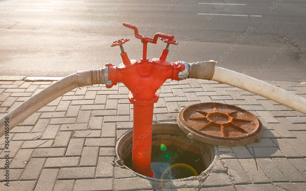 Red fire hydrant installed in open hatch with attached fire hose. Fire ...