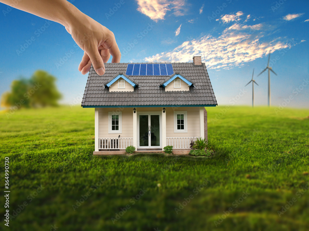 Hand and House with solar panel on the roof with wind turbine on ...