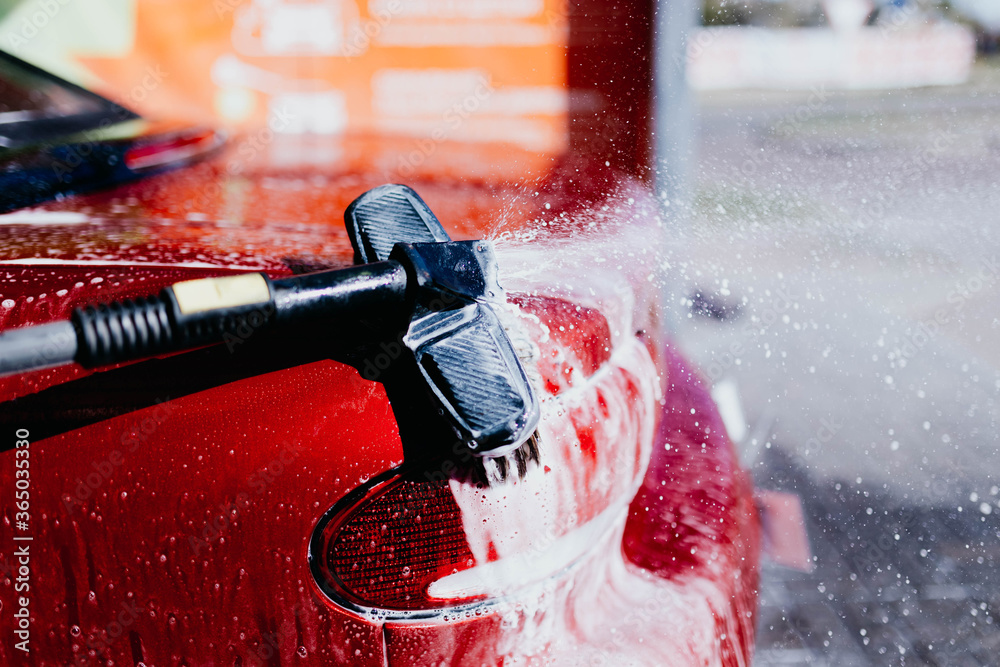 washing a red car with a compressor with water. Stock Photo | Adobe Stock