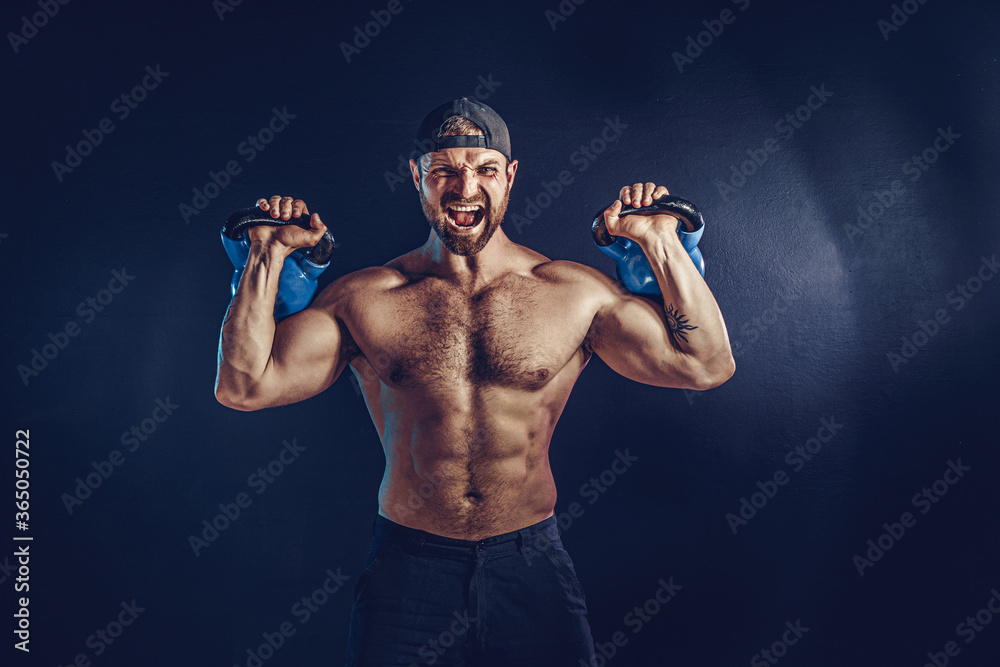 Aggressive bearded muscular bodybuilder doing Exercise for the shoulder ...