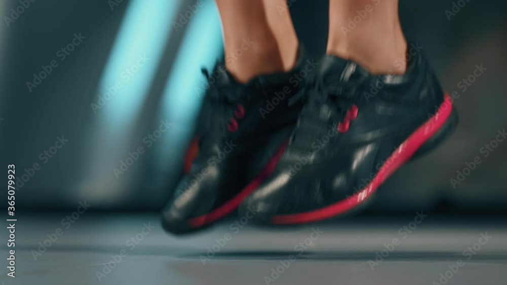 A female feet in sneakers jumping with a skipping rope. Workout with ...