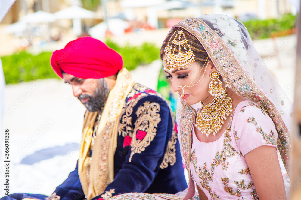 Sikh bride and groom next to each other during marriage ceremony in ...