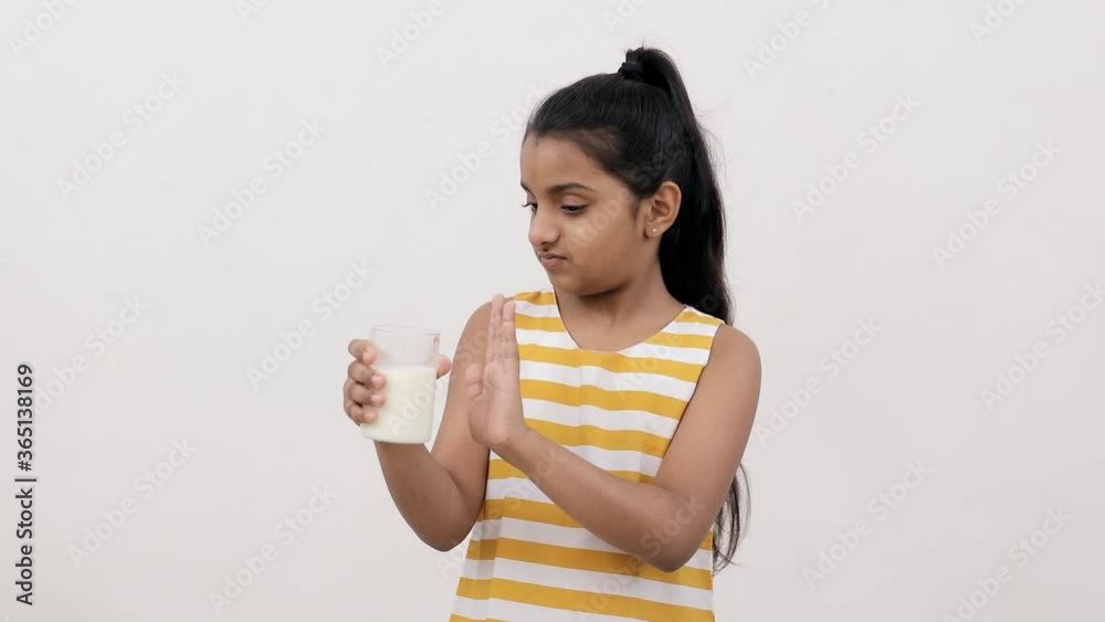 Medium shot of a little girl denying a glass of milk due to stomach ...