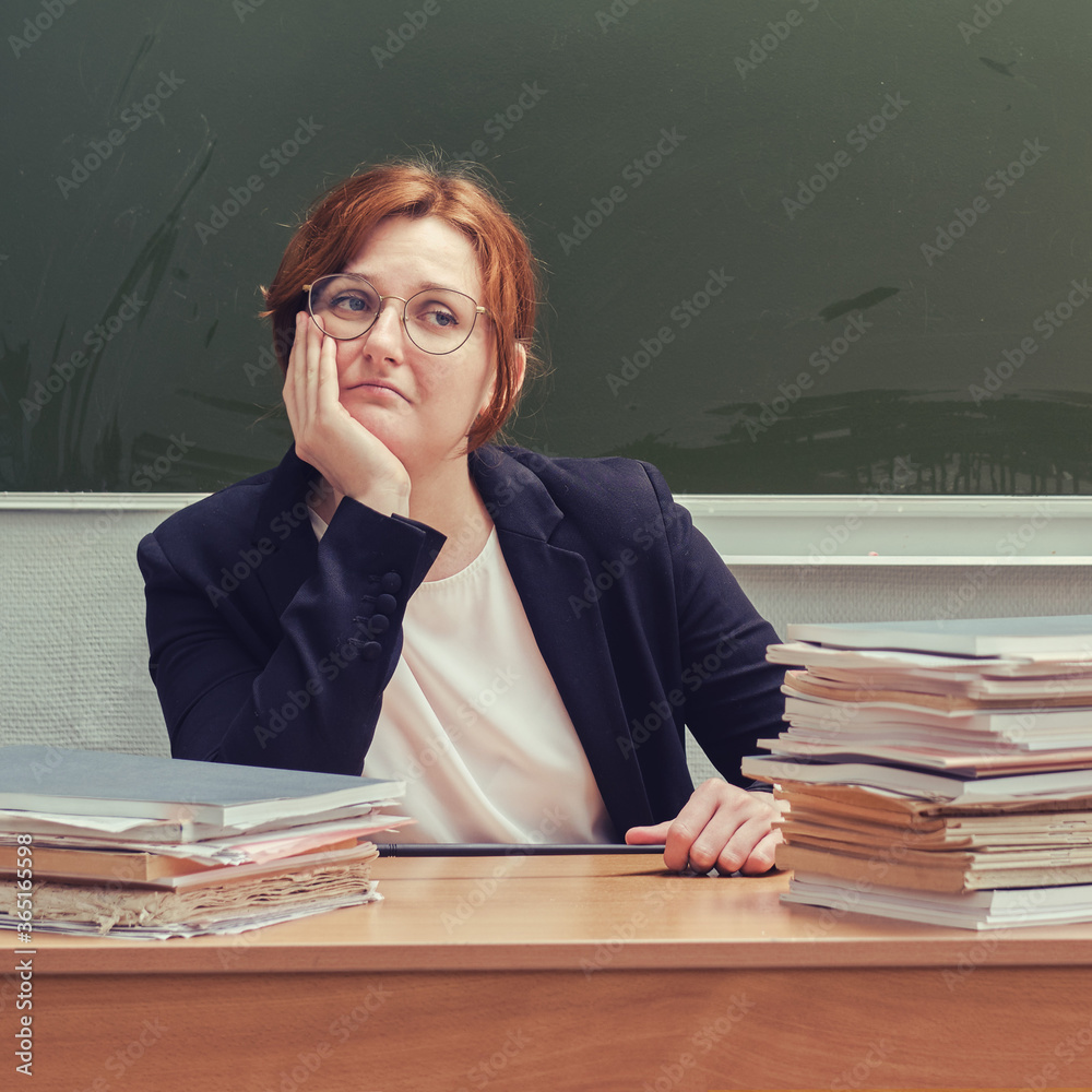 Woman teacher with a sad face at the blackboard. School teacher is sad ...