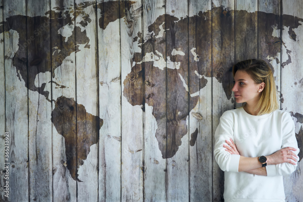 Young female with crossed arms standing against world map with seven ...
