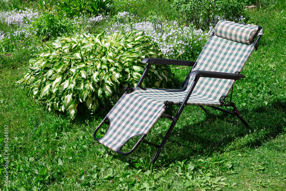 A light checkered folding chair for sunbathing in nature stands on the ...