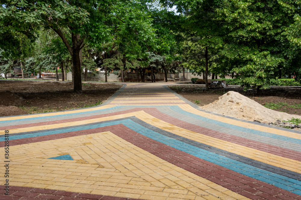 Laying colored concrete paving slabs in the park. Professional workers ...