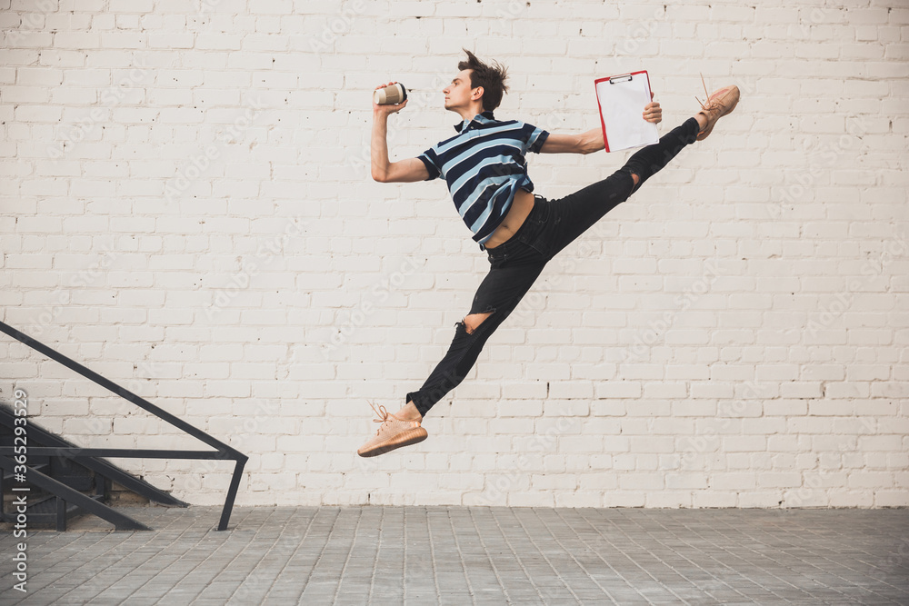 Foto de Jumping young buinessman in front of city building wall, on the ...