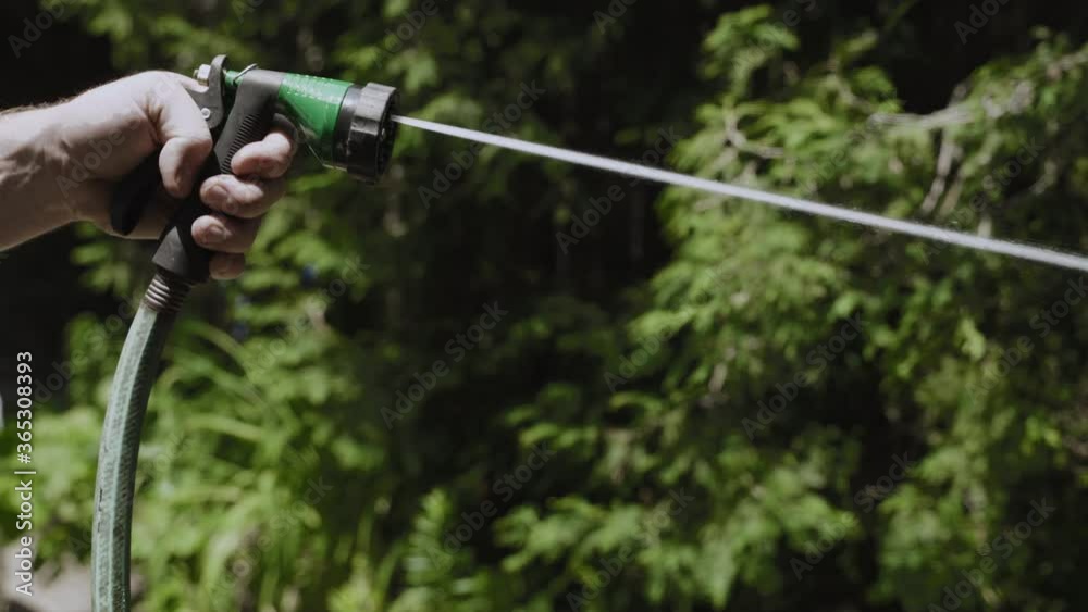 Man's hand holding a hose with nozzle set to the jet spray setting ...