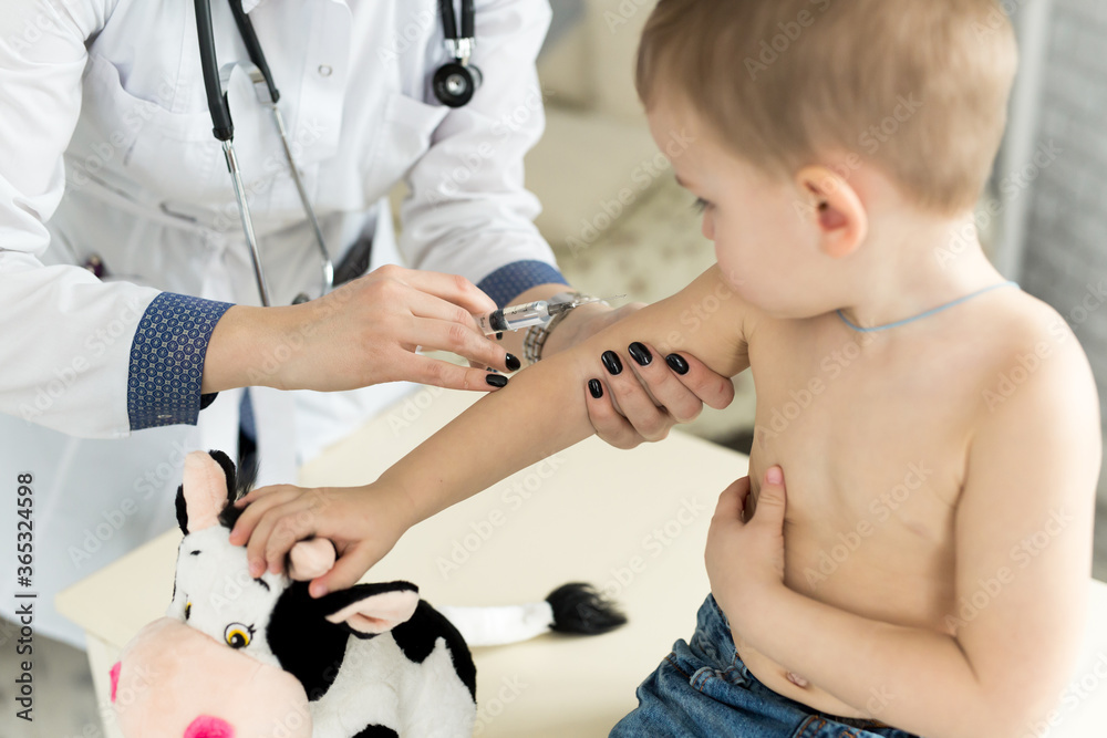 Doctor pediatrician giving child an intramuscular injection in arm ...
