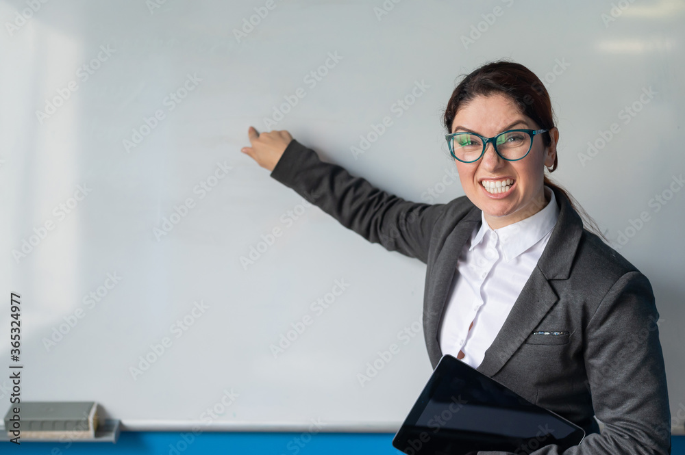 Angry teacher in suit with finger on white board in class in class. A ...