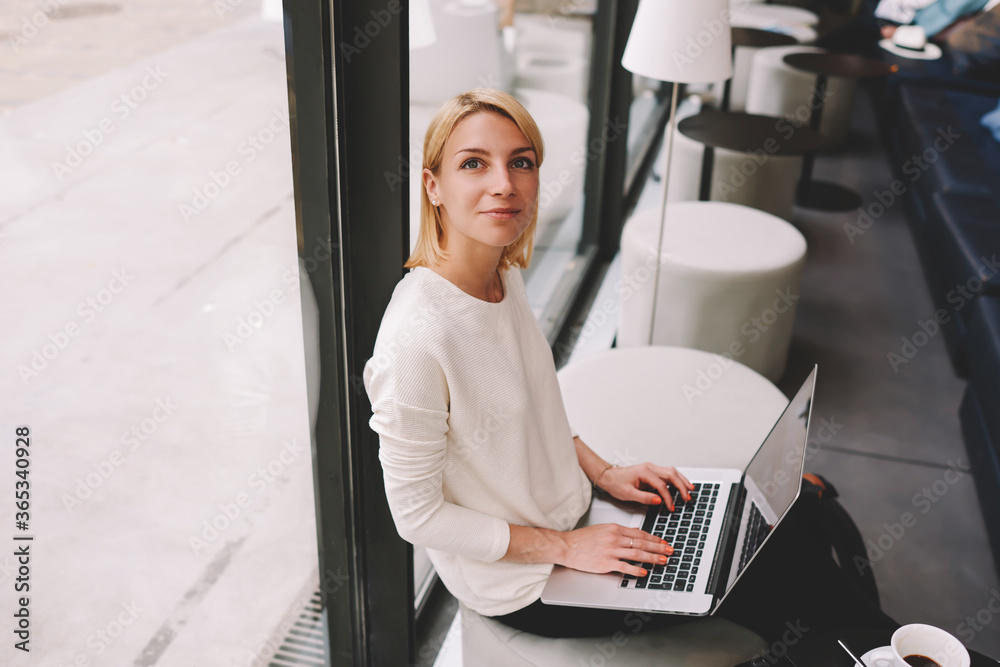 Gorgeous young woman sitting with open laptop computer in modern coffee ...