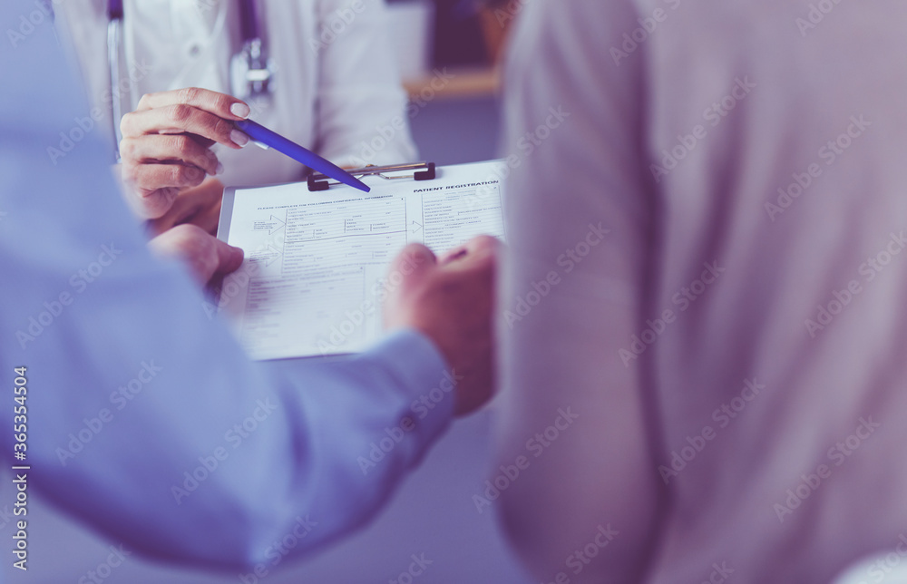 Doctor and patient examining a file with medical records, she is ...