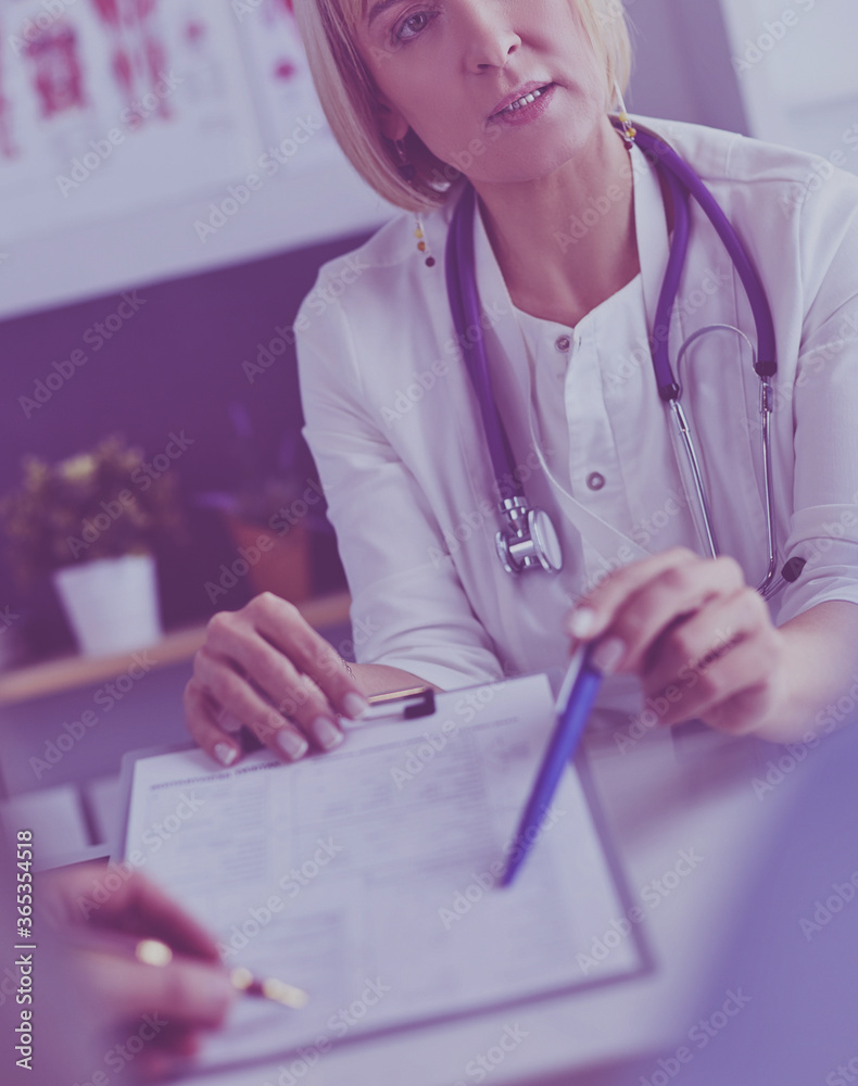Doctor and patient examining a file with medical records, she is ...