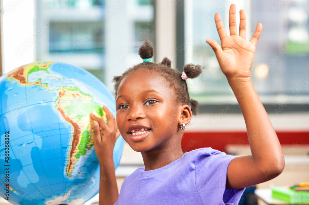 Elementary school scene. African schoolgirl using world globe in the ...