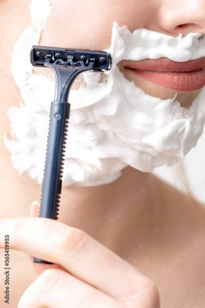 Beautiful young caucasian woman shaving her face by razor on white ...