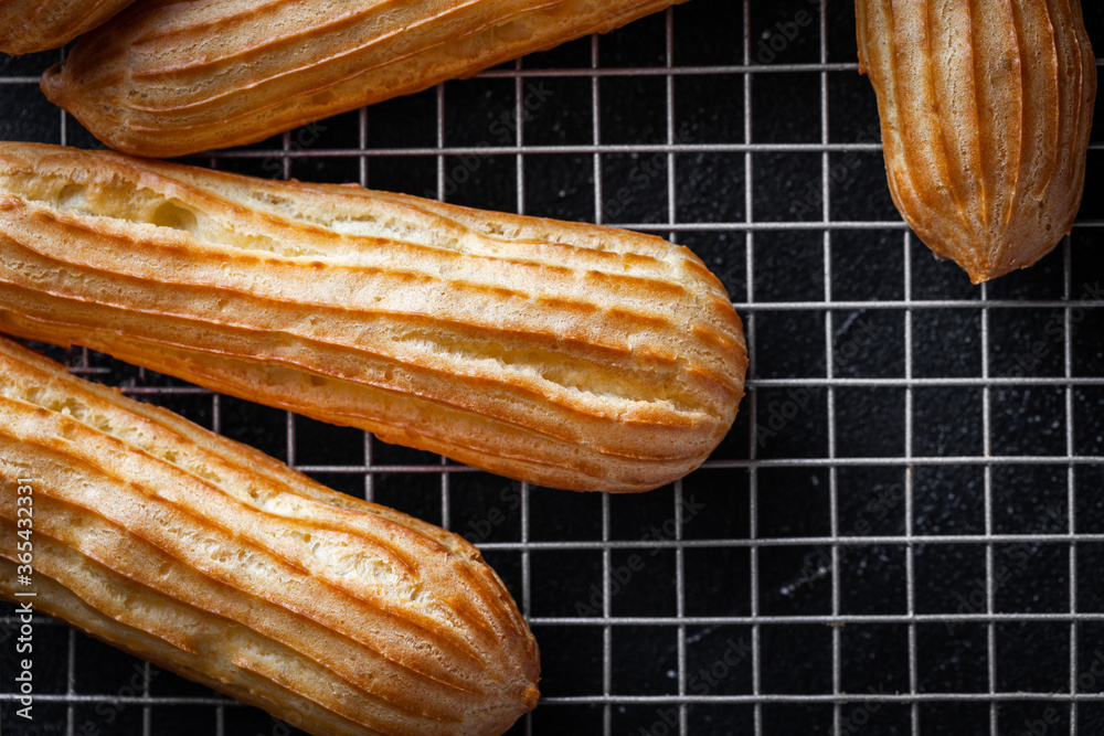 Fresh yellow toasted eclairs stacked in a pile on a pastry lattice on ...