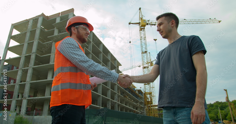 Man architects engineers and male client shaking hands at construction ...