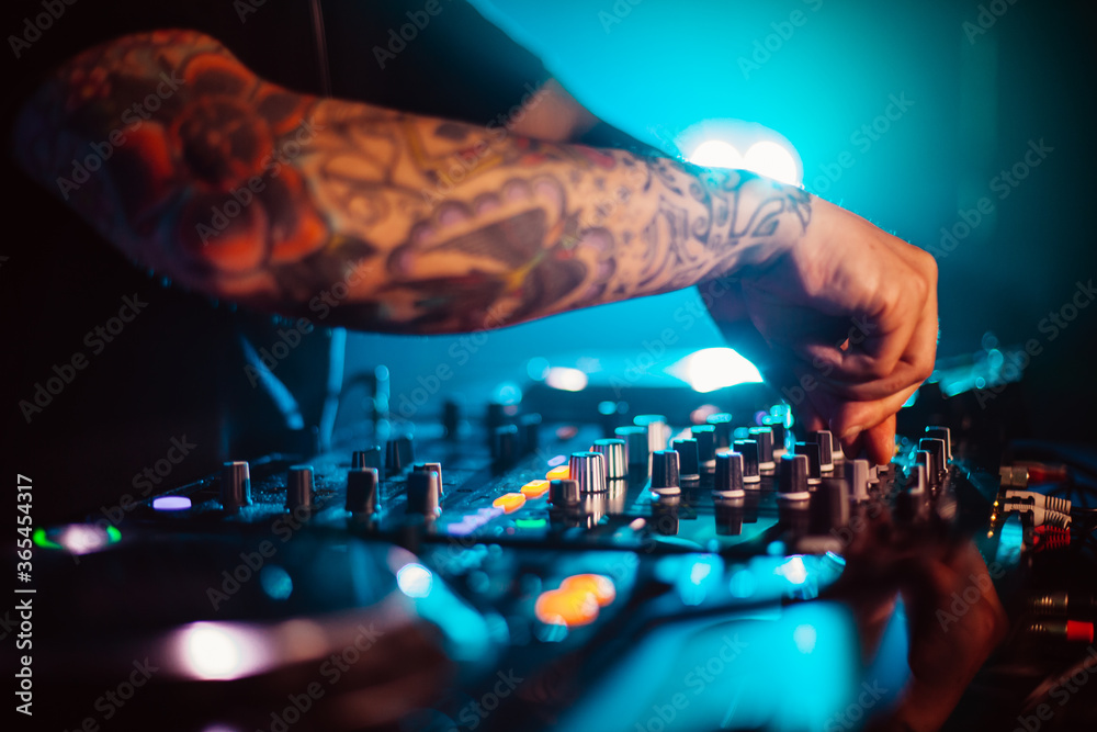Horizontal shot of a tattooed arm of a young caucasian male DJ who with ...