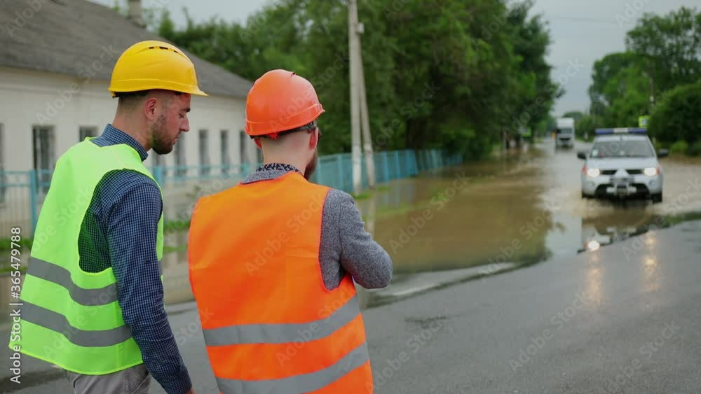 Two male engineers solve flood problem. Devastation wrought after ...