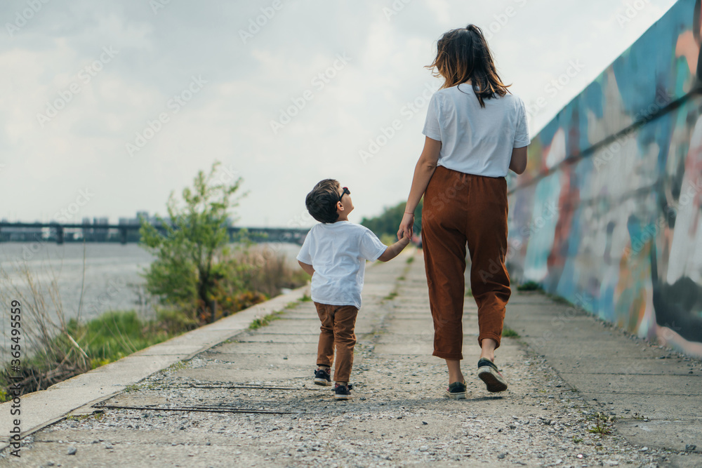 back view of mother holding hands with cute son outside Stock Photo ...