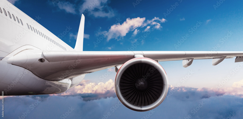 Detail of wing of commercial airplane jetliner flying above clouds in ...