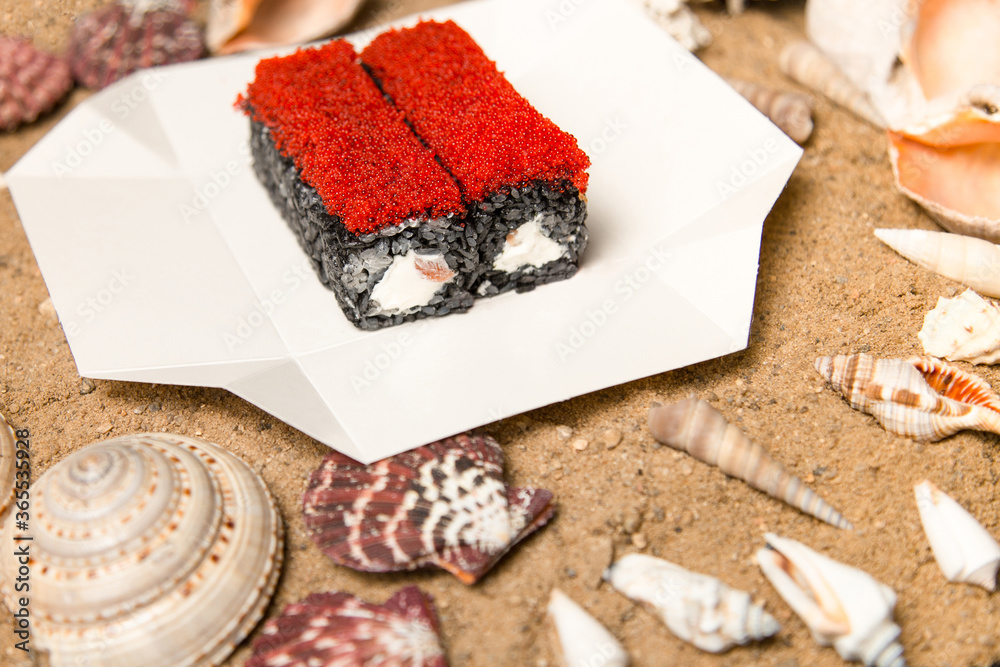 Japanese Sushi Roll in delivery box on sand background with sea shells ...