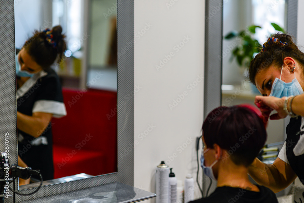 female professional hair stylist and young customer styling wearing a ...