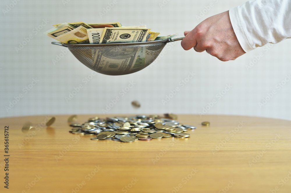 sift money through a sieve. coins fall out of the sieve. concept on the ...
