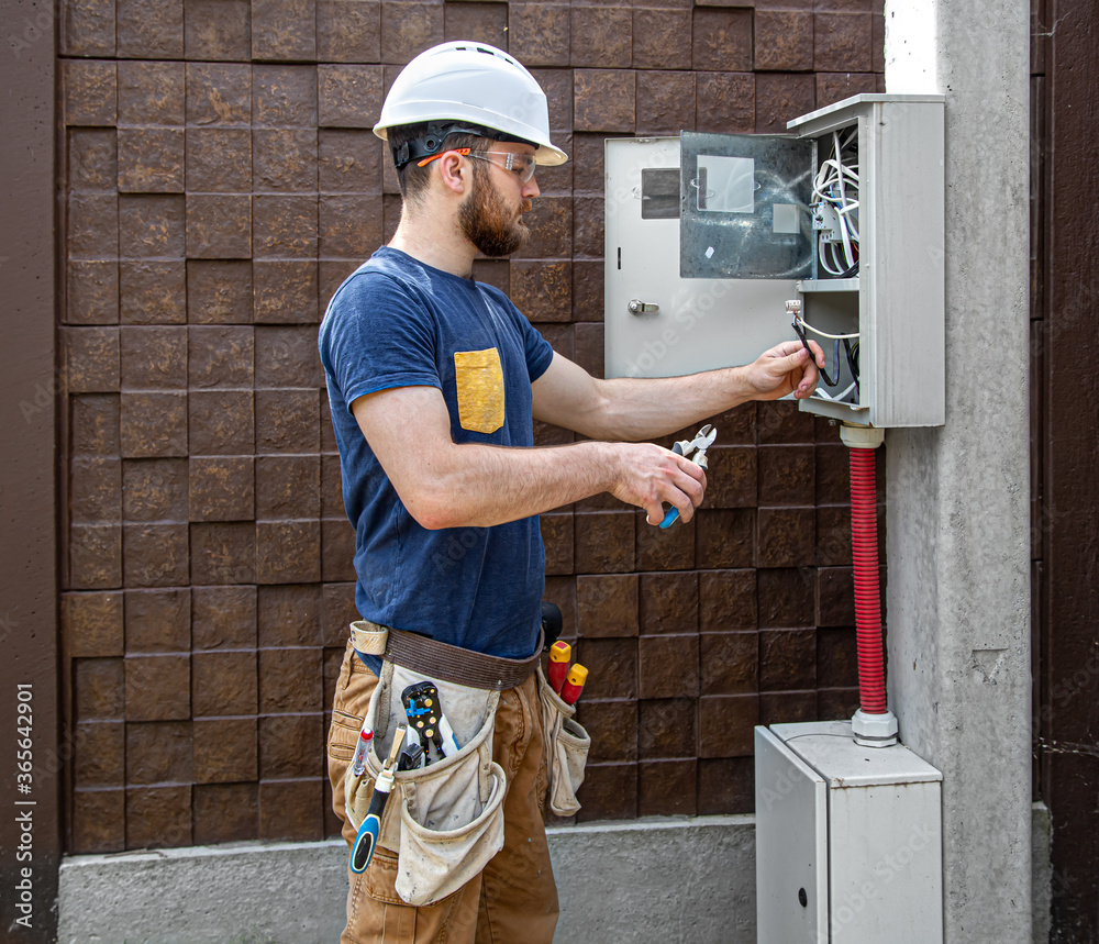 Electrician Builder at work, examines the cable connection in the ...