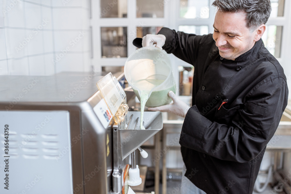 Chef pouring mixed milk base into the ice cream machine or freezer at ...
