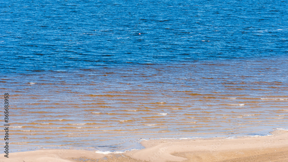 Seaside with a golden sandy bottom of shallow water and transition to a ...