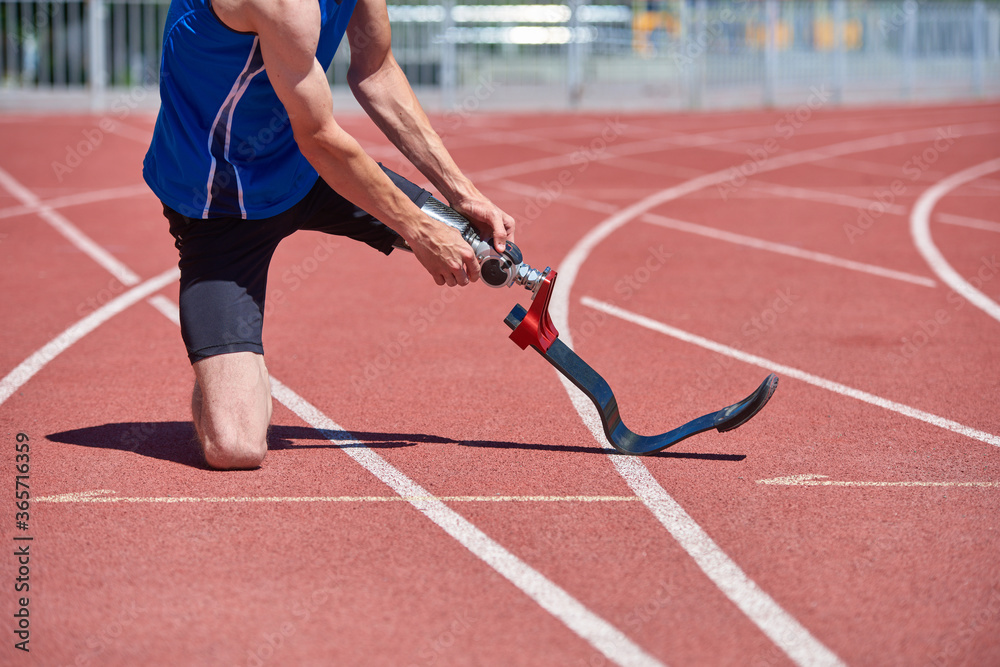 Sportsman fixing prosthetic foot at the start of running track Stock ...
