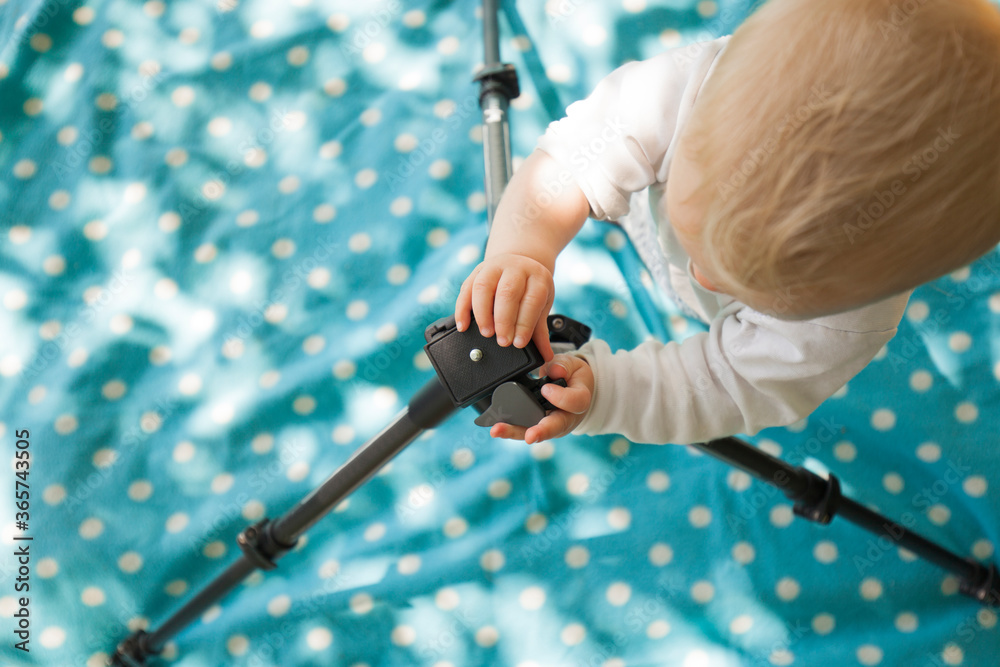 Small child learns to stand with camera tripod. Creative child stands ...