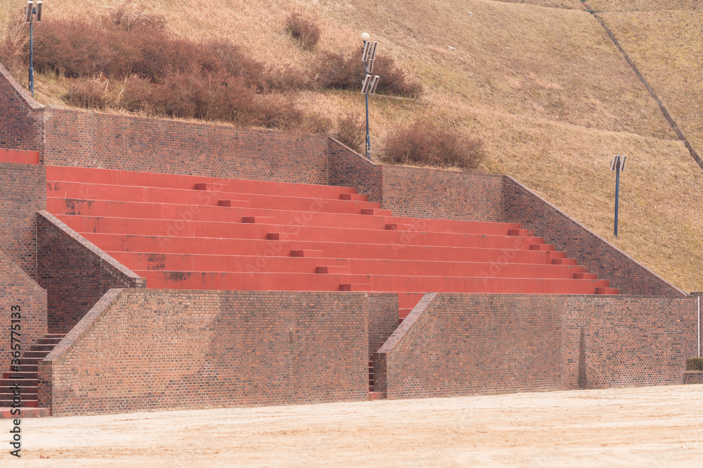 Bleachers at a football field made of red brick and concrete built on ...