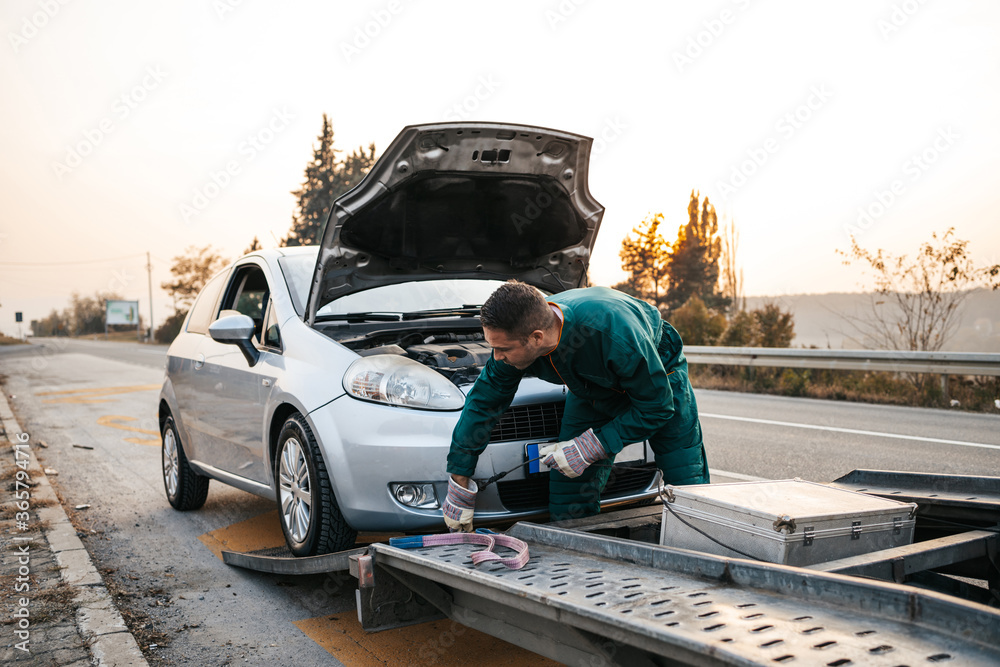 Road assistant worker in towing service trying to start car engine with ...