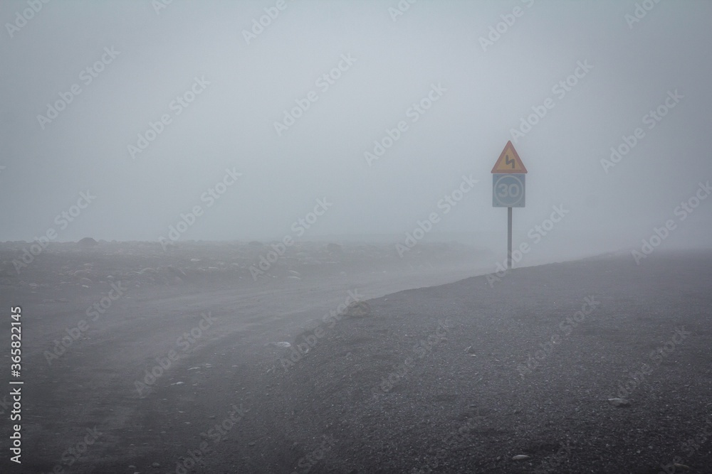 Blue speed limit and yellow windy road signs in foggy Iceland. Stock ...