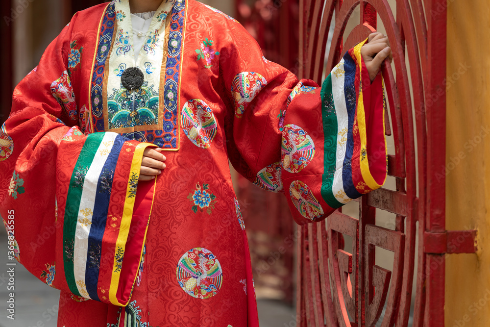 detail of traditional Vietnamese red silk robes. Model is standing next ...