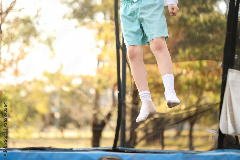 Little boy jumping high on trampoline in socks without face showing ...