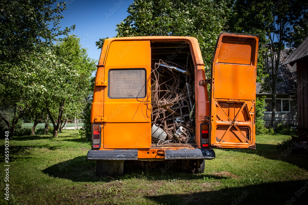 Rear view of an old orange vintage van with the right back door opened ...