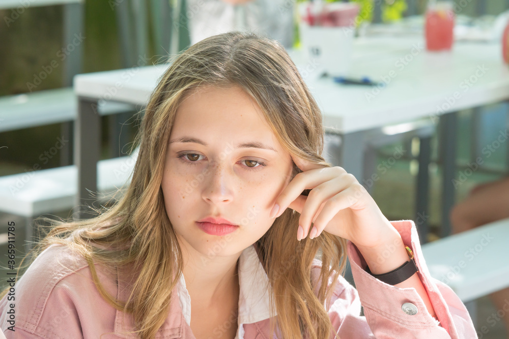 Sad looking girl holding touching her face with her hand and thinking ...