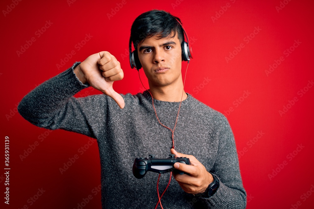 Young handsome gamer man playing video game using joystick and ...