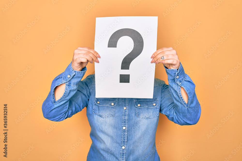 Woman covering face holding paper with question mark symbol. Standing ...