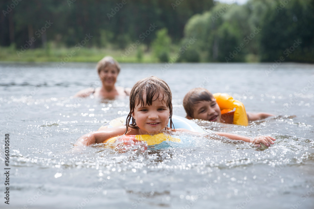 Happy kids swimming in the lake on hot summer day. Kids learn to swim ...