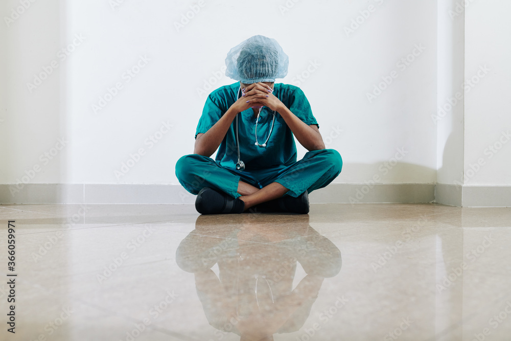 Crying stressed and tired medical nurse sitting on floor of hospital ...